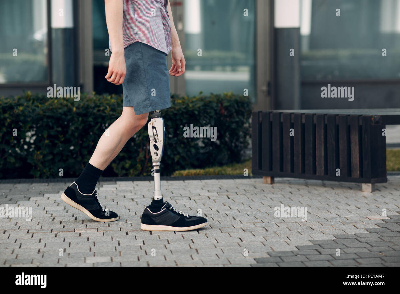 Disabled young man with foot prosthesis walks along the street Stock ...