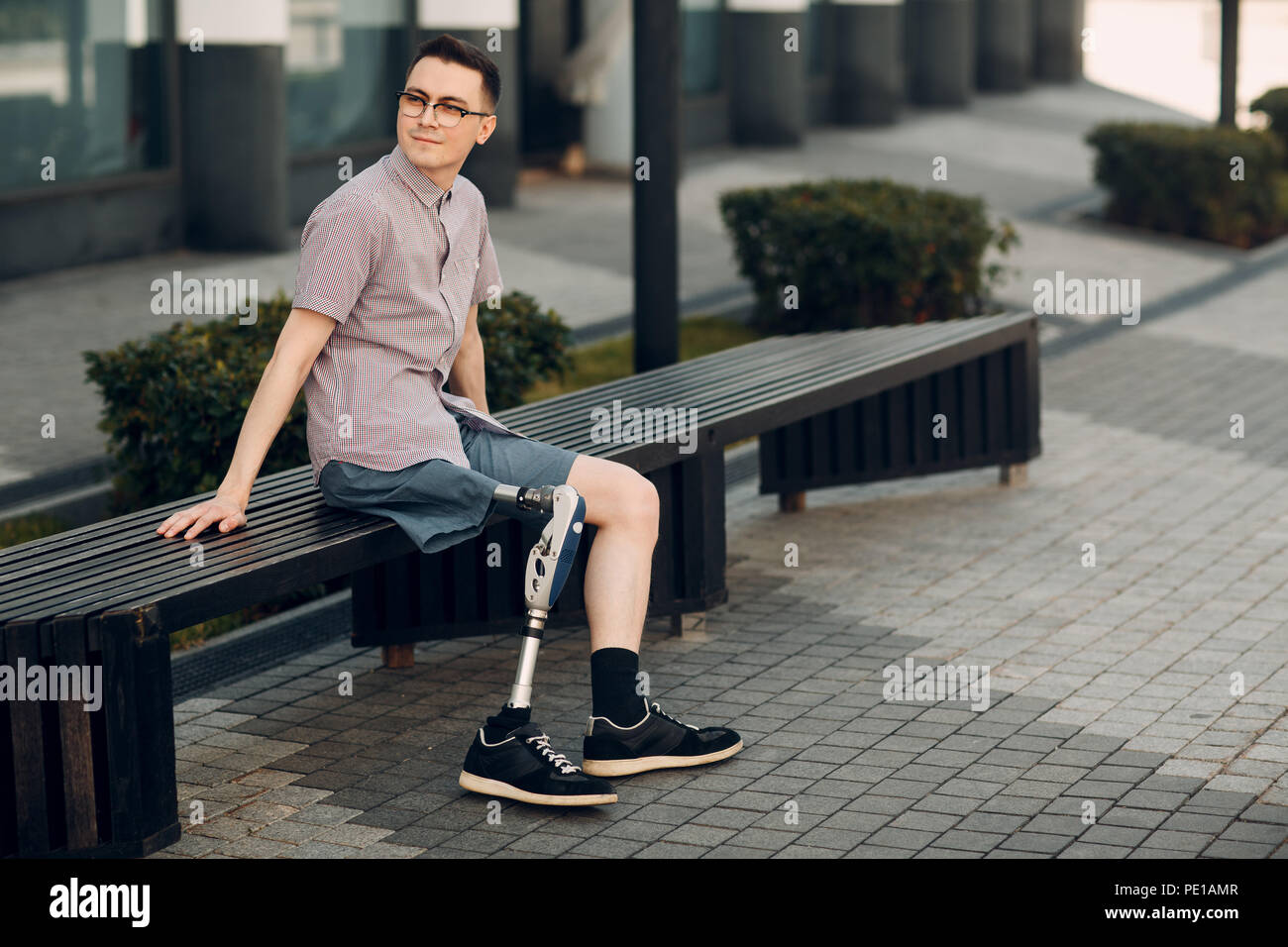 Disabled young man with foot prosthesis sitting outdoor Stock Photo - Alamy