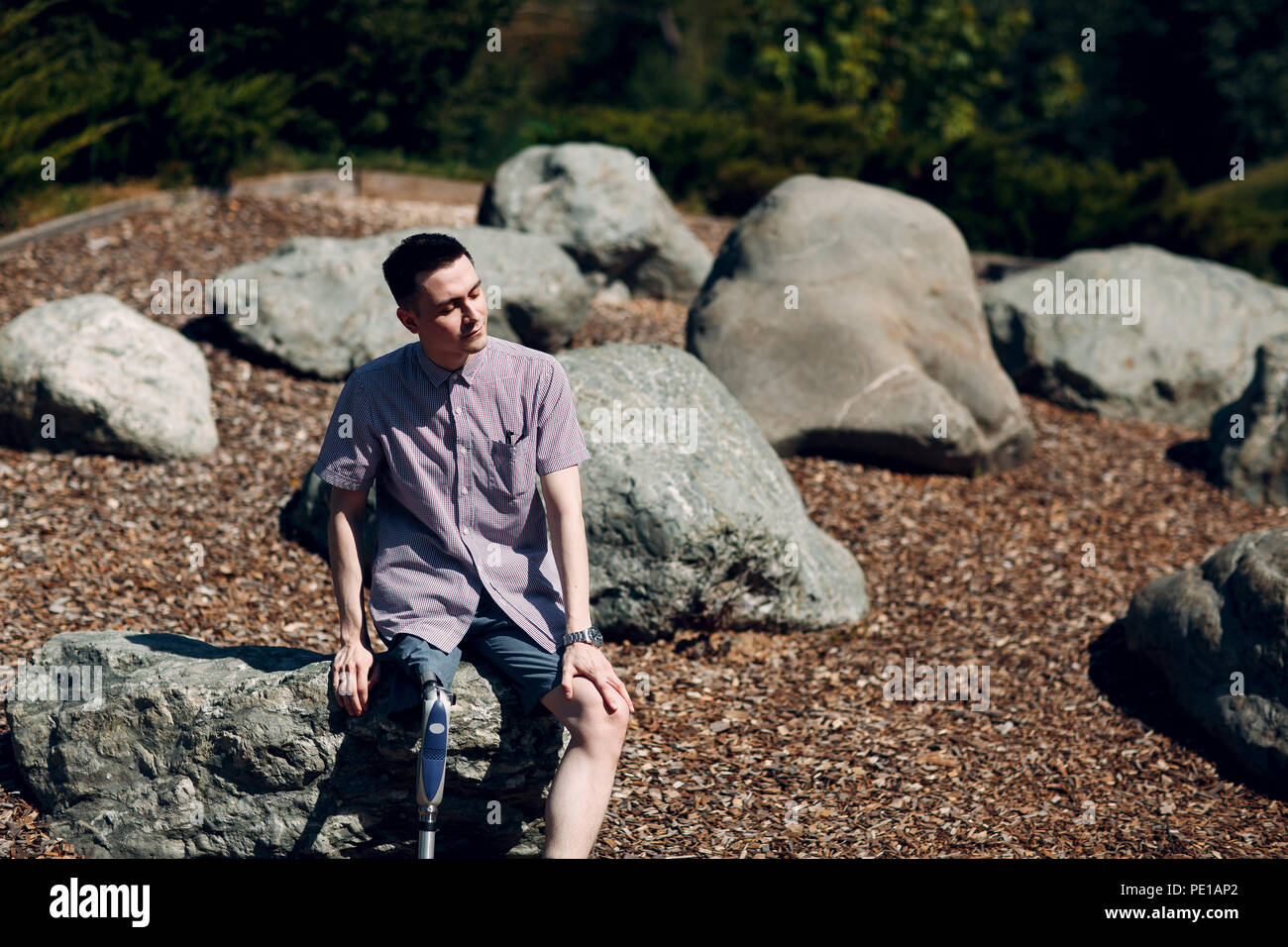 Disabled young man with foot prosthesis sitting on stone Stock Photo ...