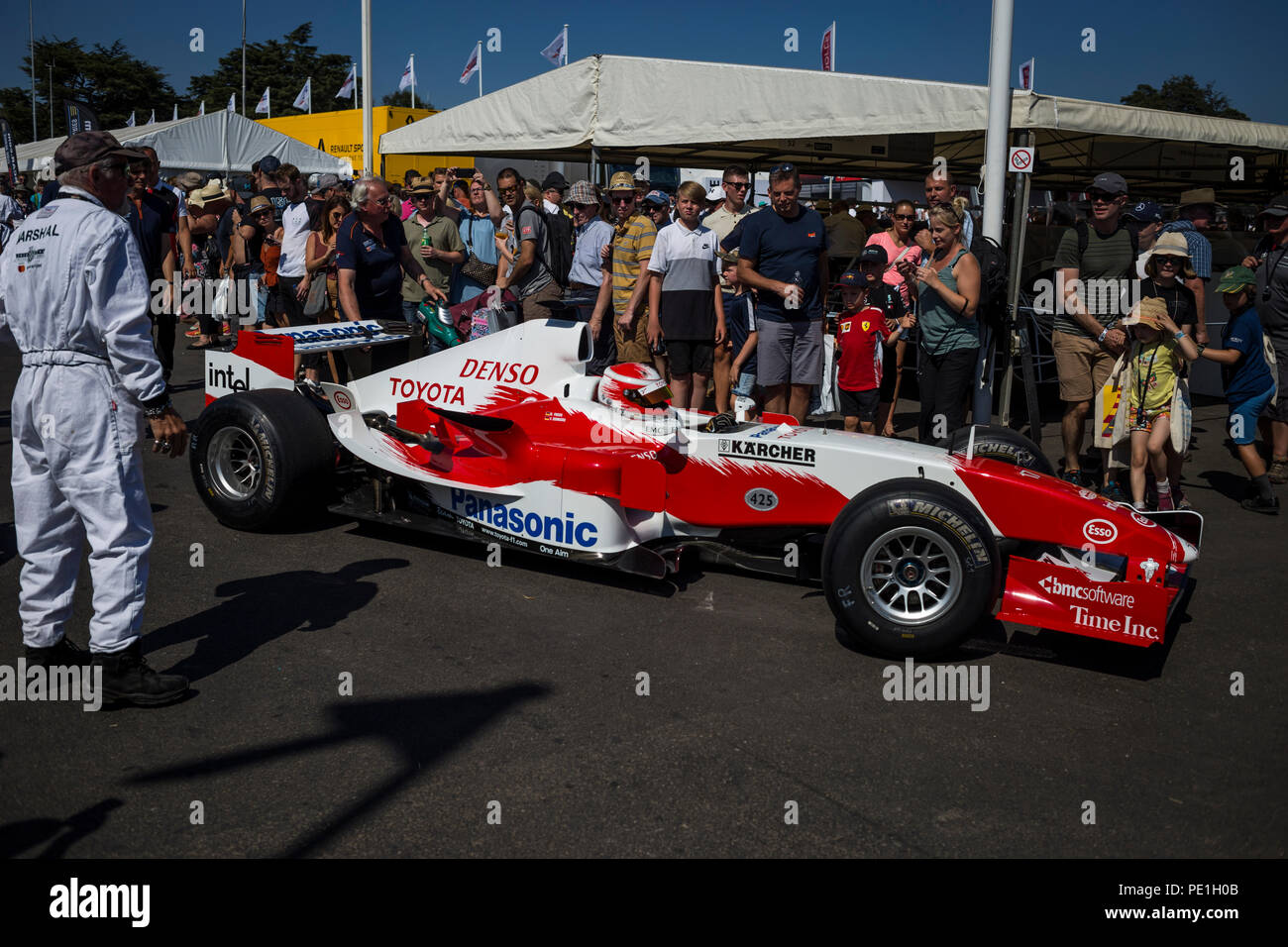 A Formula One car returning to the paddock through a crowd at the ...