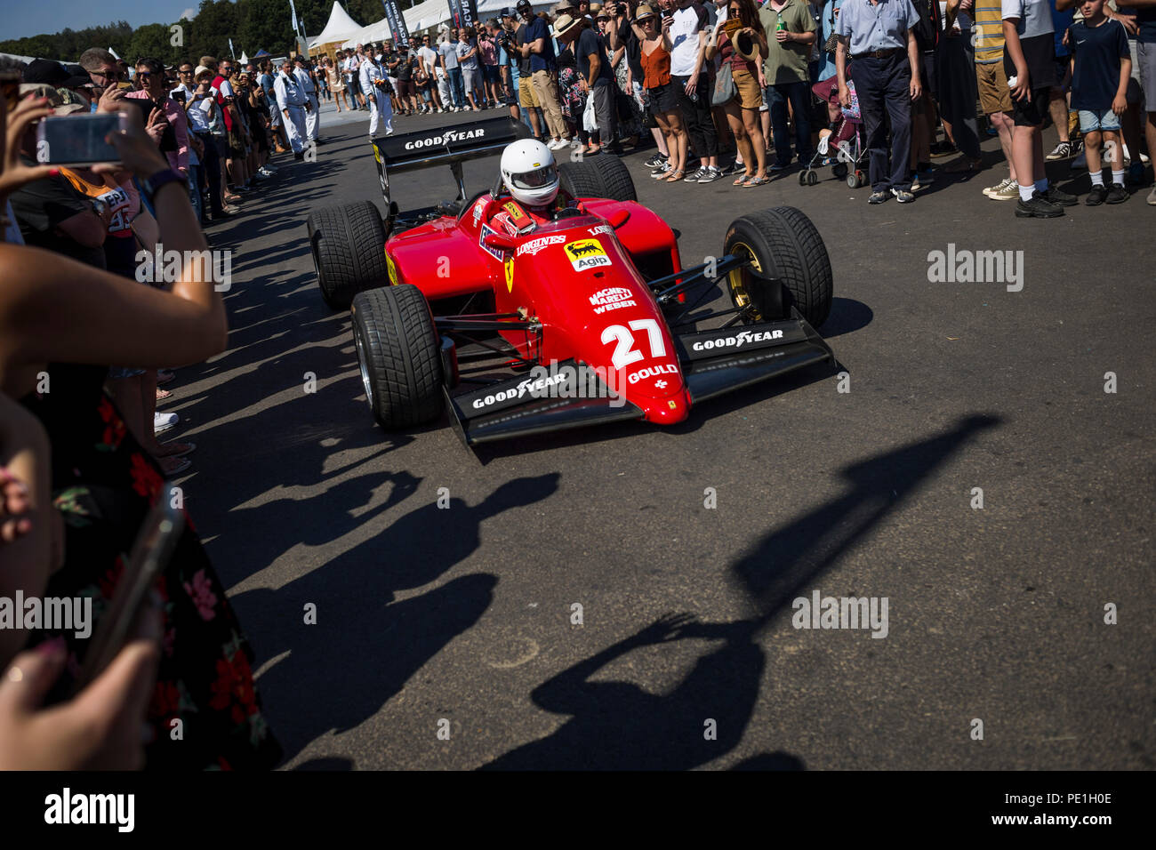 A Formula One car returning to the paddock through a crowd at the ...