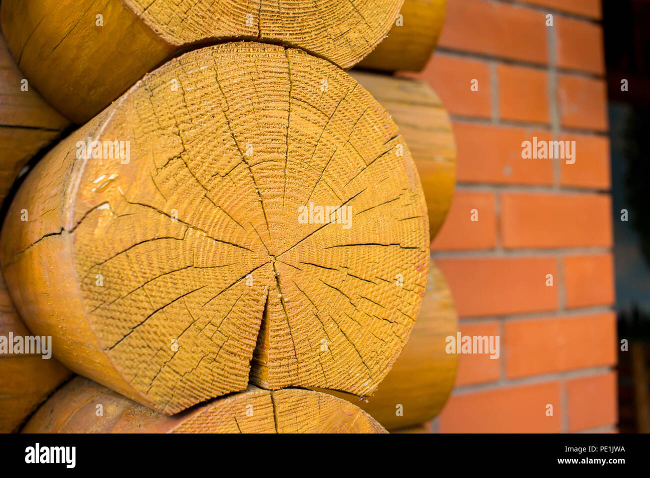 Round wooden log house closeup with red brick wall background Stock ...