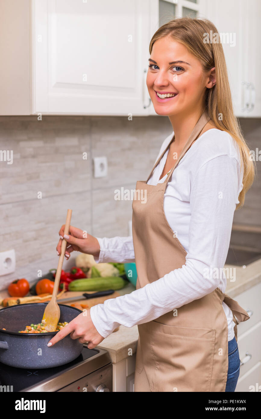 Beautiful woman cooking meal in her kitchen Stock Photo - Alamy