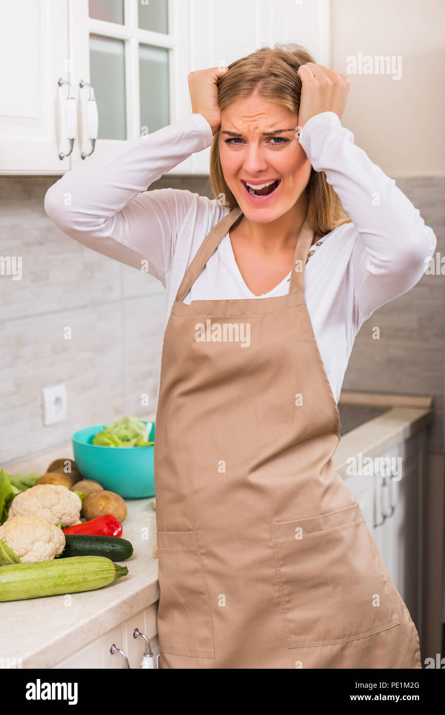 Angry woman screaming in her kitchen while making meal Stock Photo - Alamy