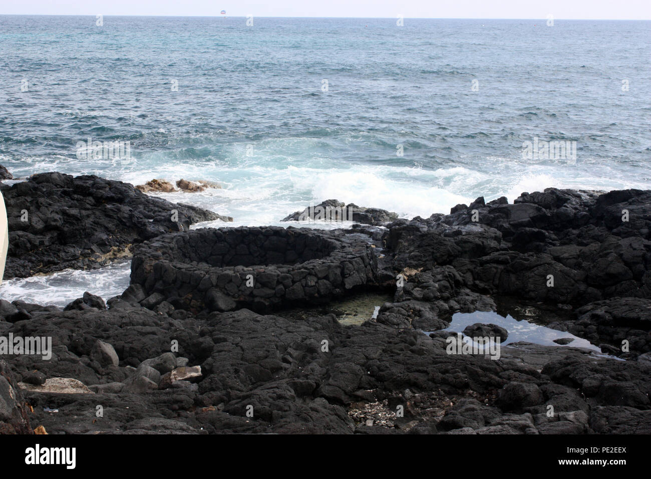 A man made tub using volcanic rock along a rocky, volcanic shoreline ...