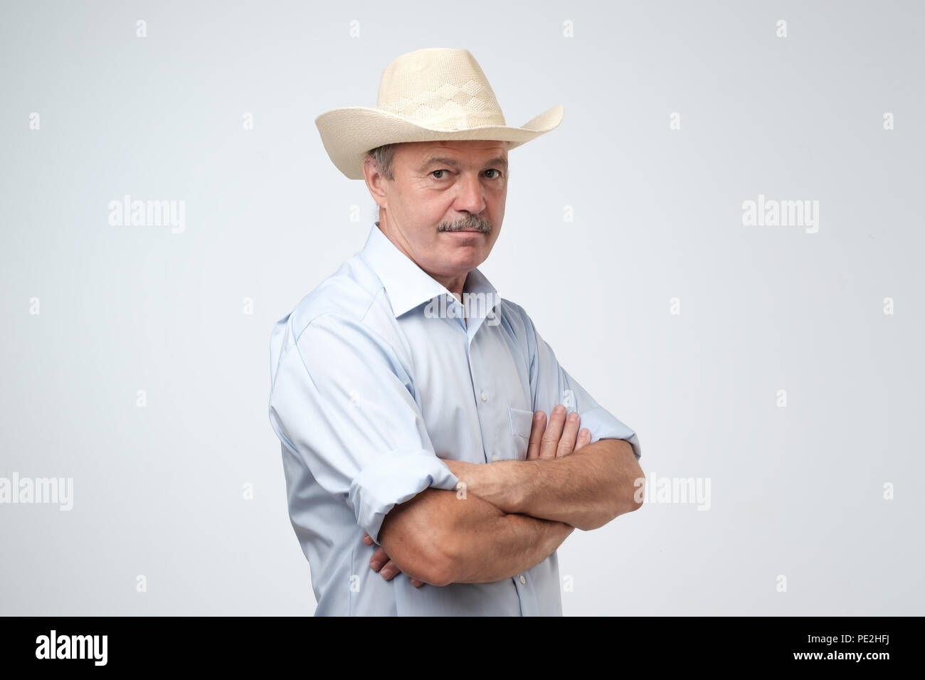 Cowboy style. Mature man adjusting his cowboy hat and looking at camera ...