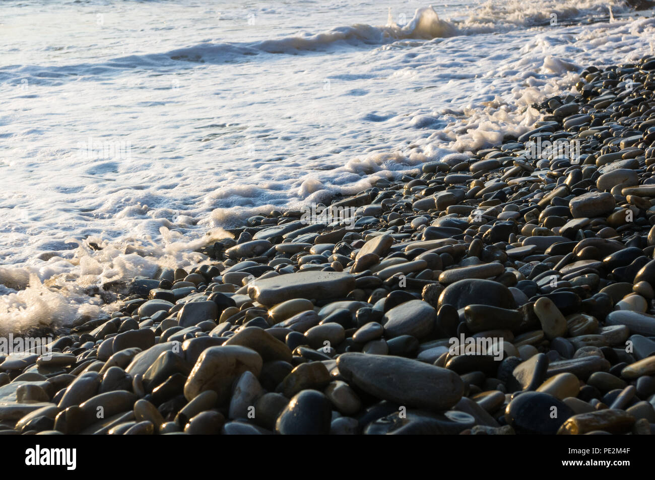 pebble stones on the sea beach on a warm summer day, the rolling waves ...