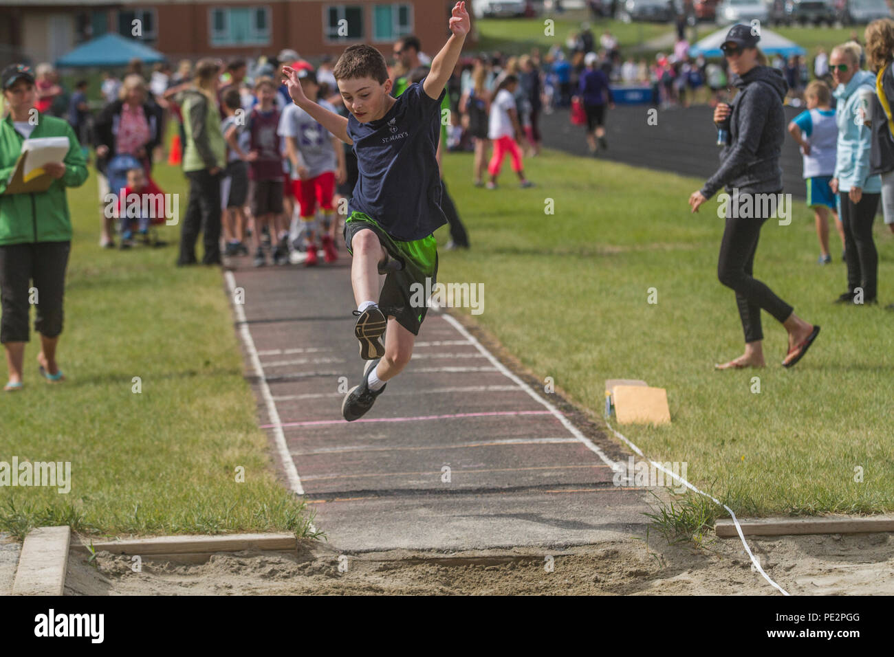 Young boy competing in track & field's trple jump, wearing t-shirt and ...