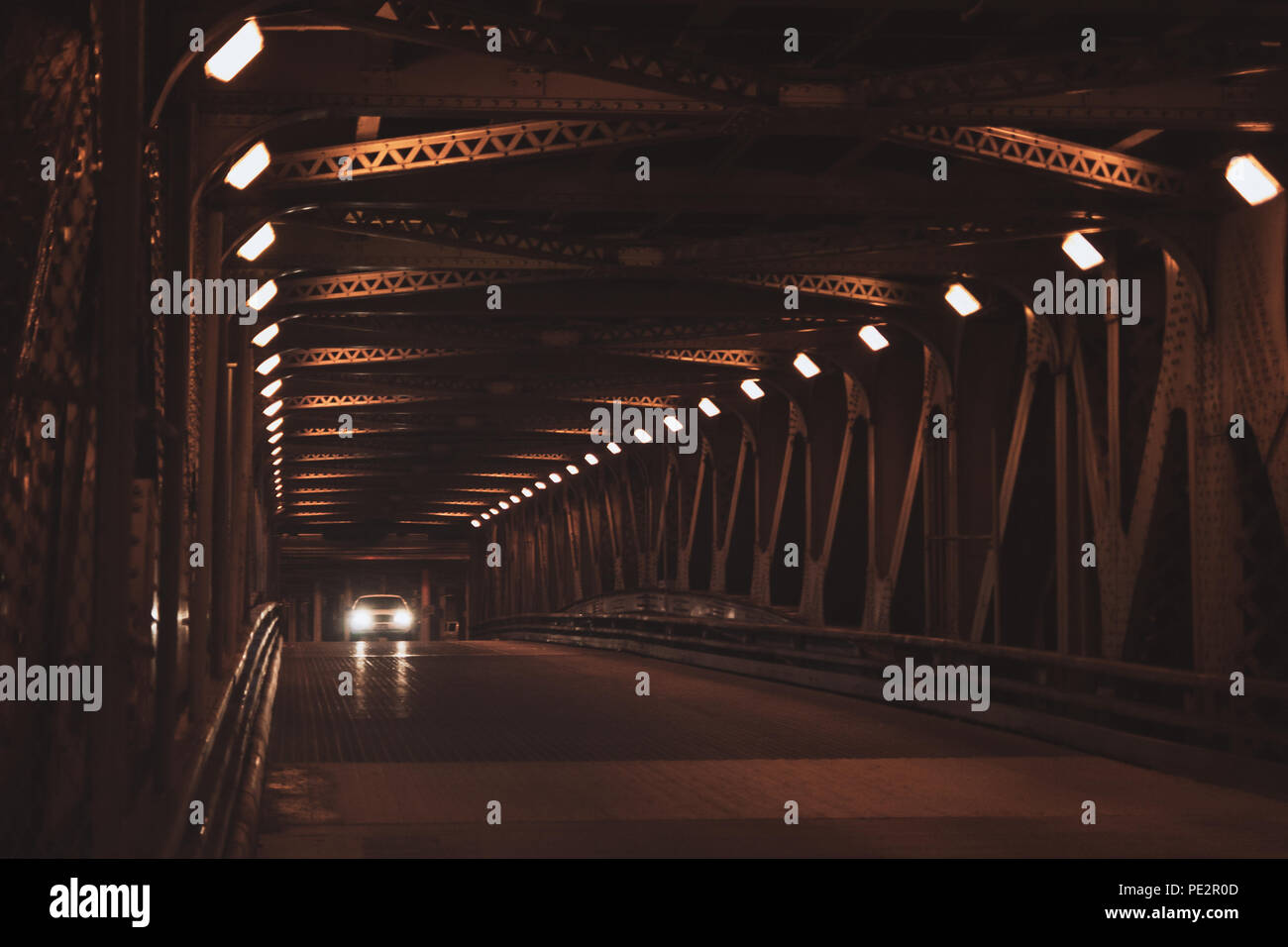 Car in the distance in a lower street tunnel viaduct bridge steel ...