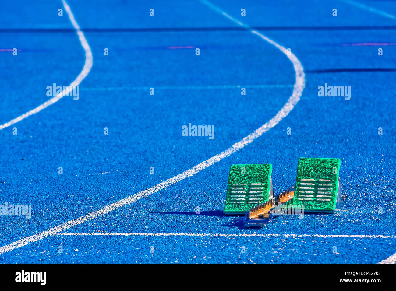 Green starting blocks in a lane of a blue track Stock Photo - Alamy