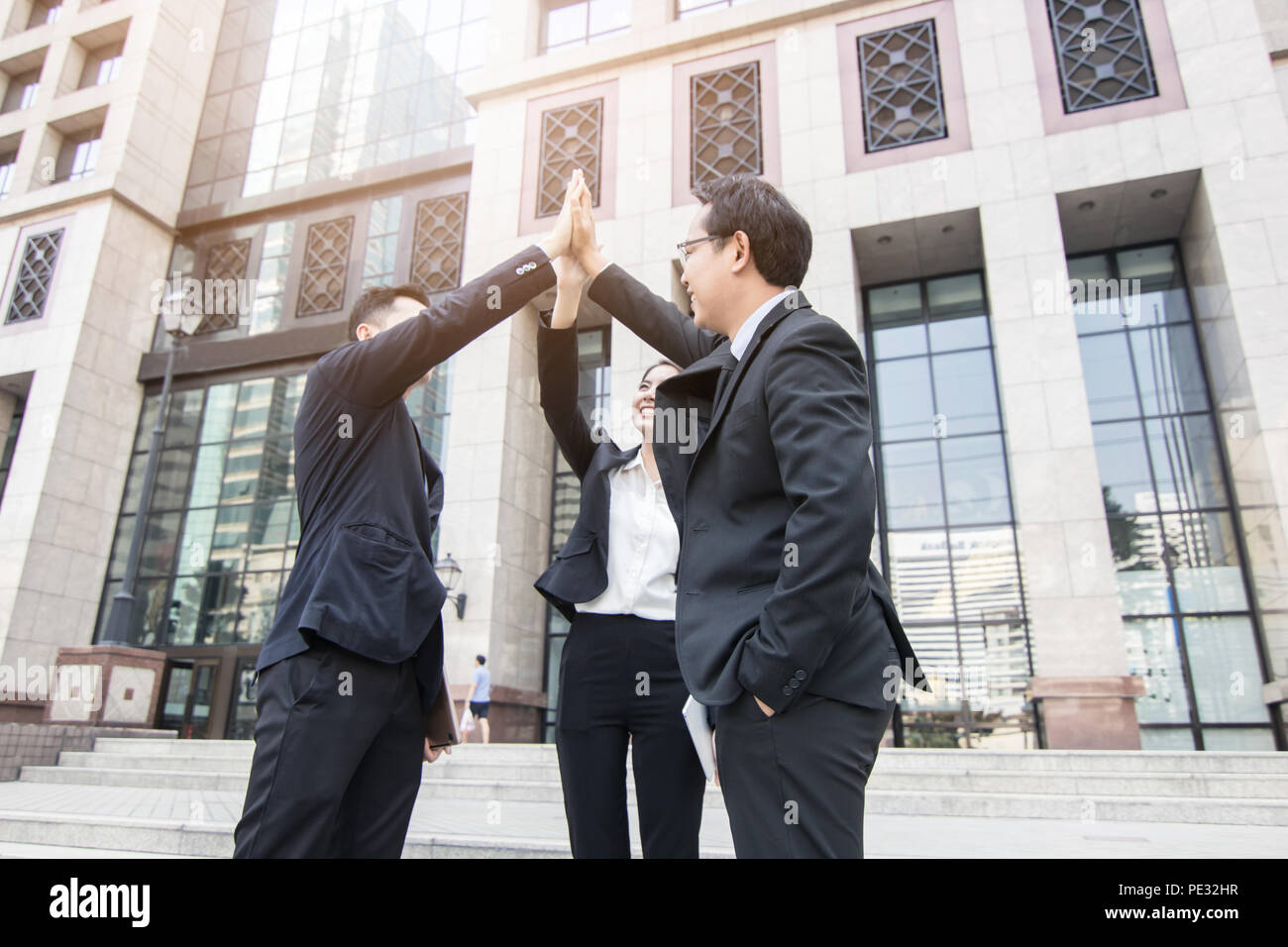 Hand coordination of team businessman on sky infront of bank building ...