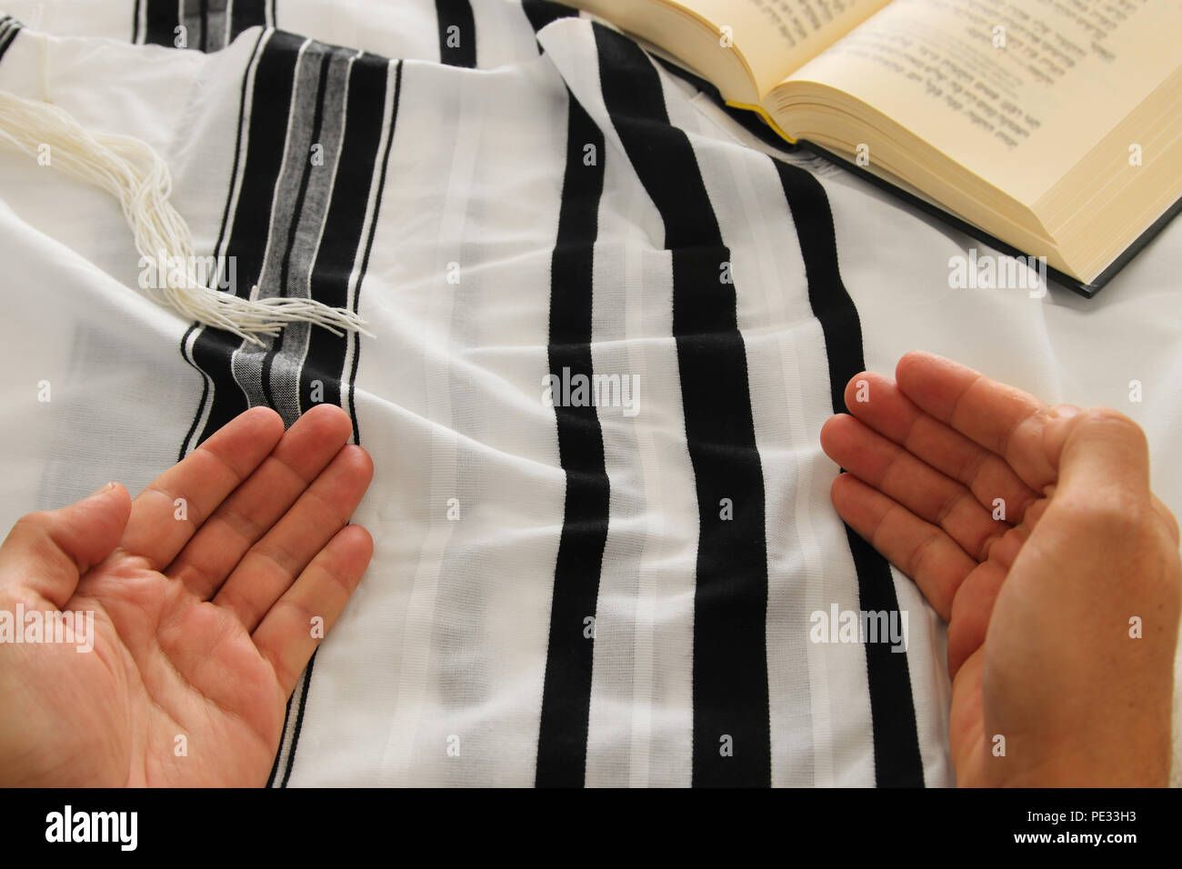 Jewish man hands next to Prayer book, praying, next to tallit. Jewish ...