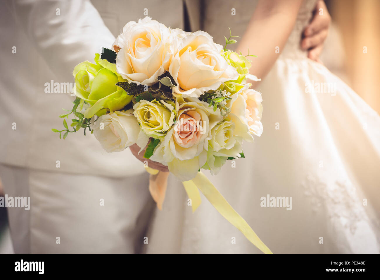 Bride and groom holding hands and a bouquet of flowers as a token of ...