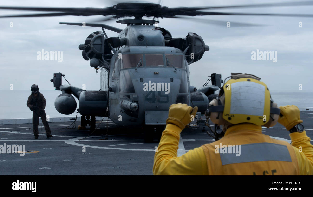 A Sailor aboard the USS Somerset directs an MH-60R Seahawk helicopter ...