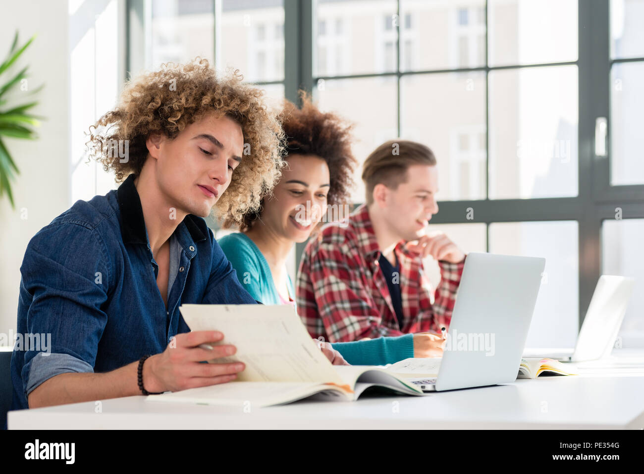 student in front of a book while sitting down at desk Stock Photo - Alamy
