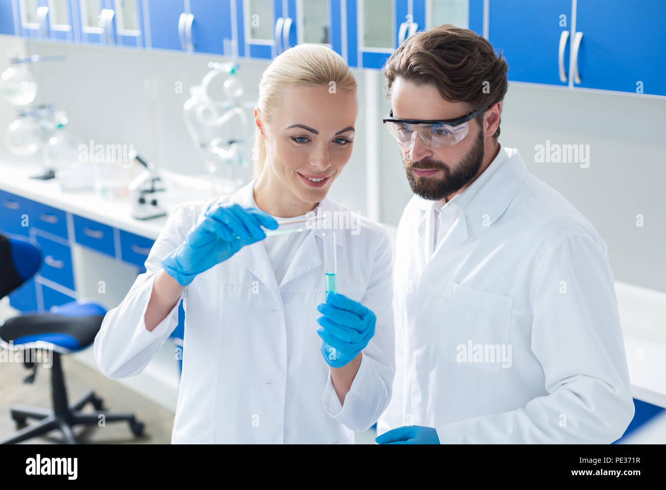 Modern chemistry. Nice positive cheerful woman holding test tubes and ...