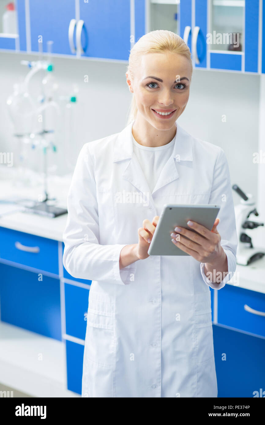 Innovative tablet. Joyful positive nice woman standing in the lab and ...