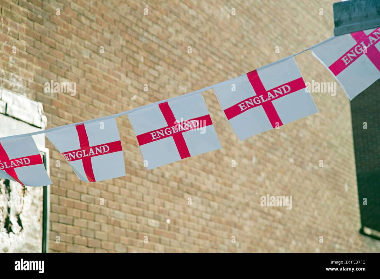 A string of plastic England flags with a deteriorated sign board of a ...