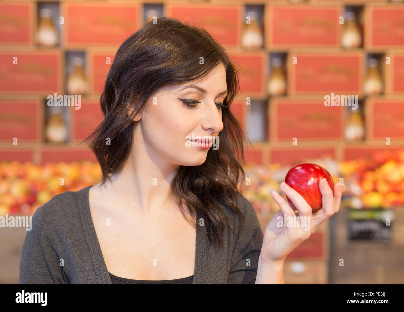 Girl in grocery store holding a red apple while smiling Stock Photo - Alamy