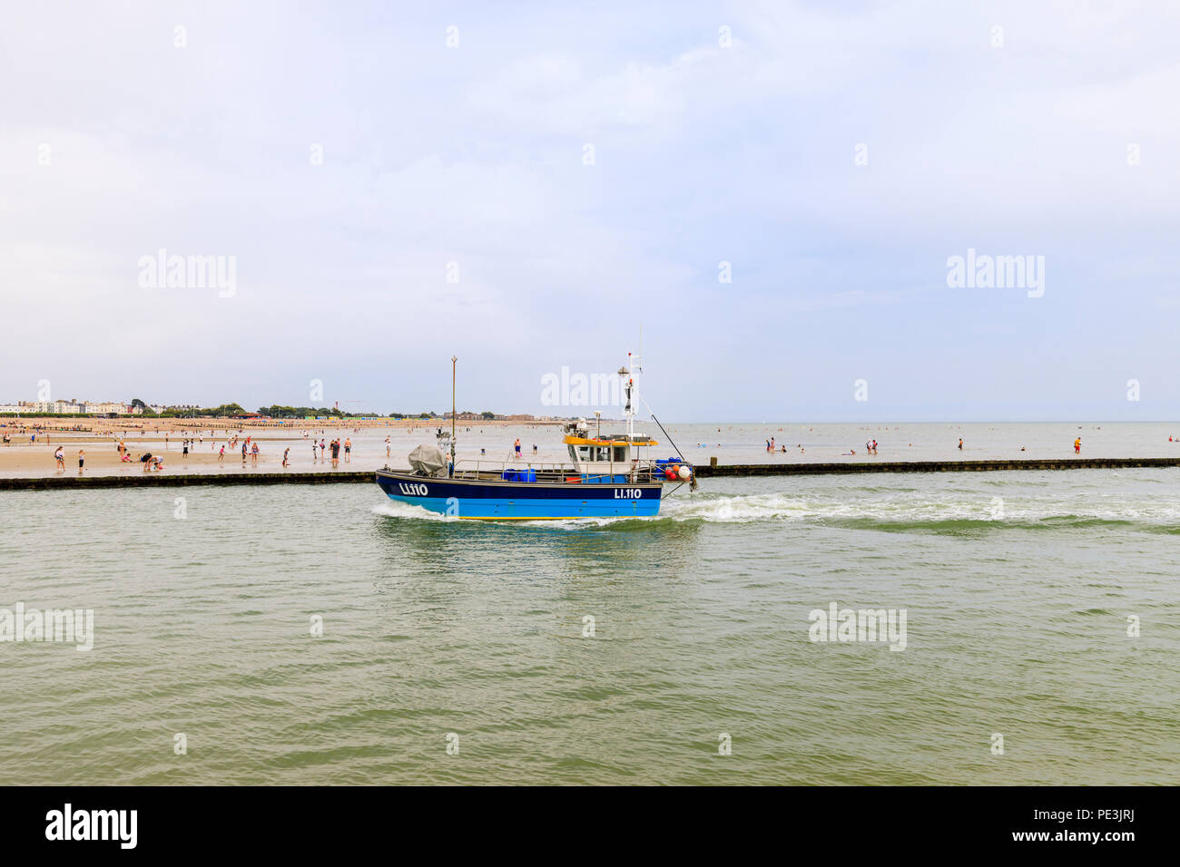 A small blue fishing boat returns entering the River Arun estuary at ...