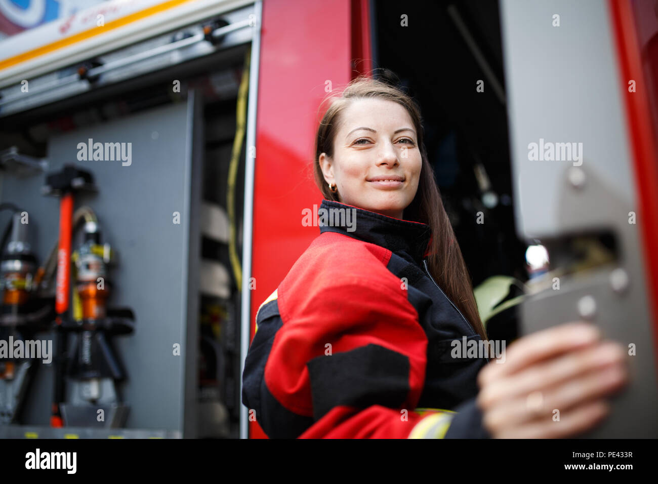 Photo of young fire woman with long hair looks at camera next to fire ...