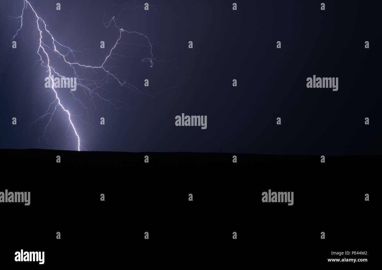 Single lightning strike in nature in a field with colours of white and ...