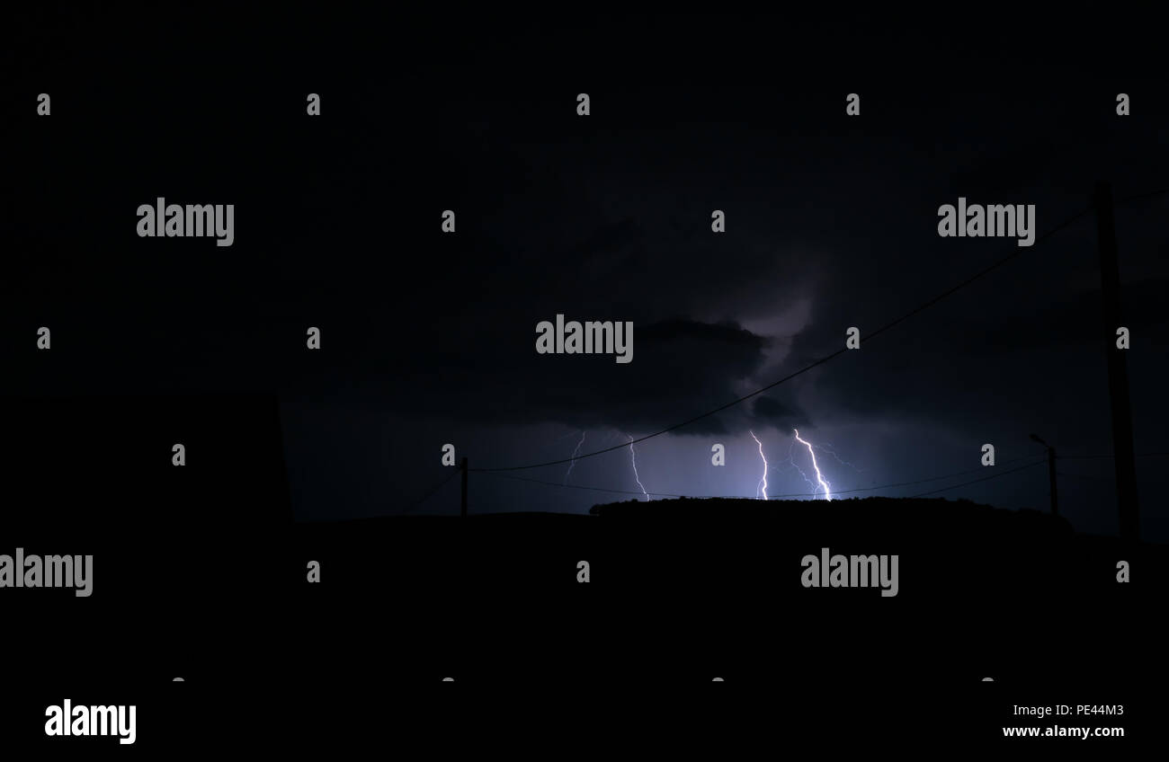 Single lightning strike in nature in a field with colours of white and ...