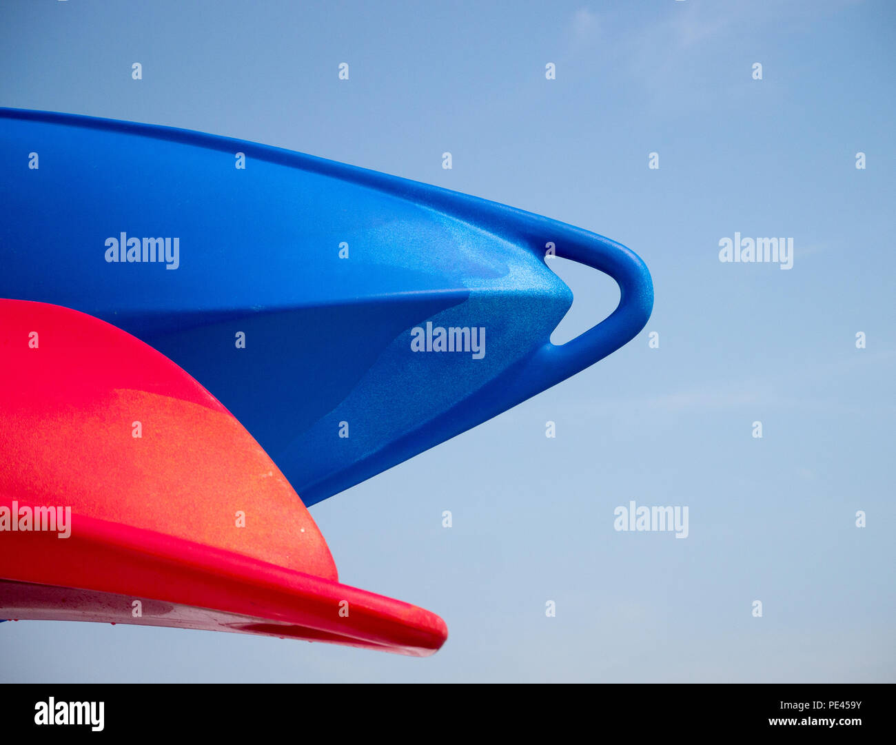 Colour close up of the noses of two sea kayaks, one blue, one red ...