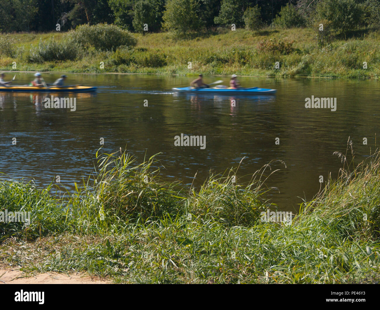 Two kayaks with people floating down the river in a hot summer day ...