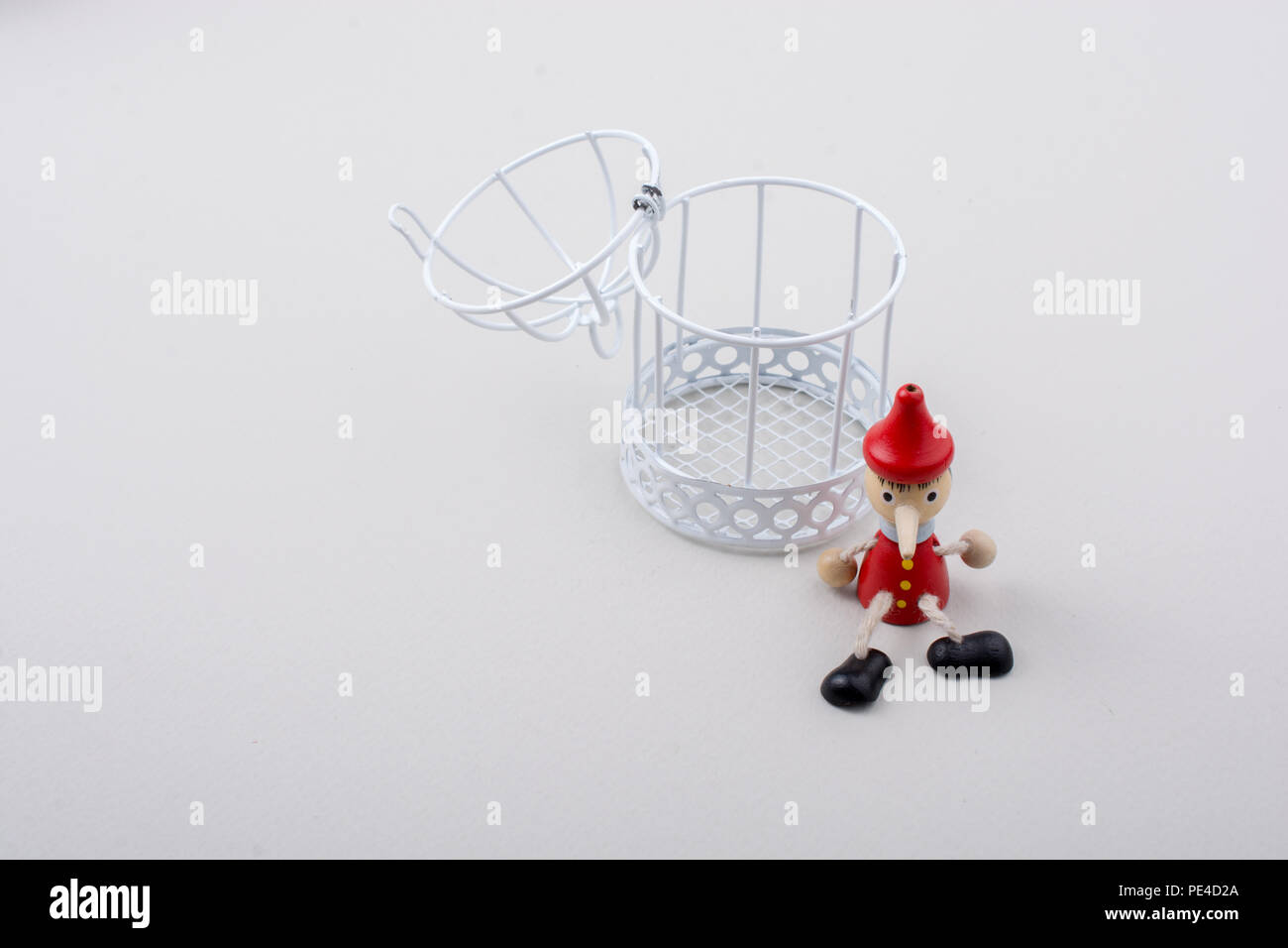 Metal cage and Little puppet pinocchio made of wood Stock Photo - Alamy