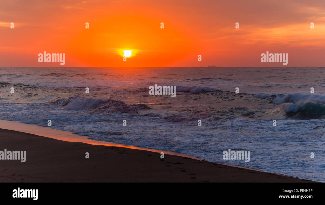 Morning beach shoreline waves with ocean sunrise and ship on horizon ...