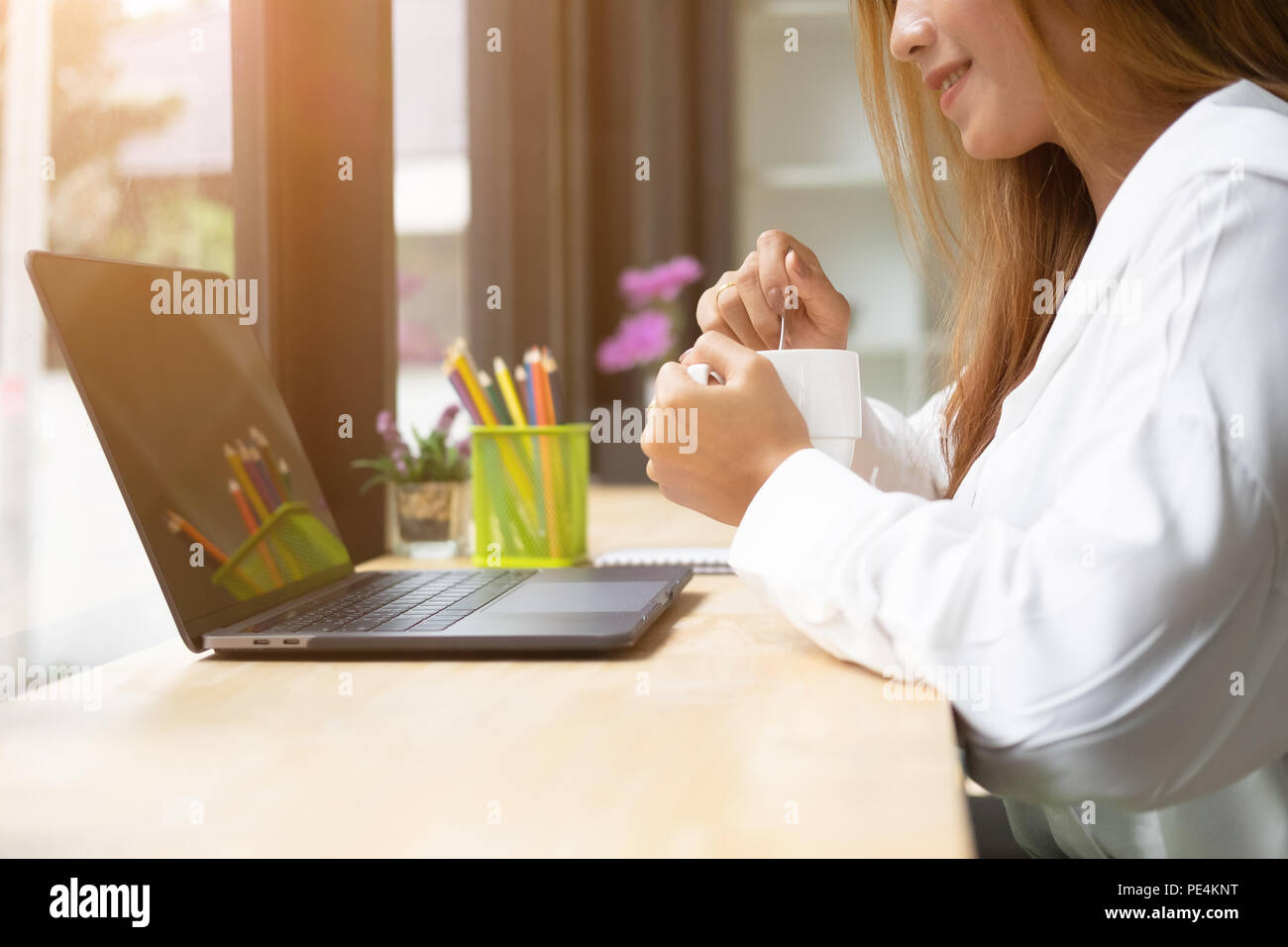 Woman holding a mug of coffee on work table office with side view Stock ...