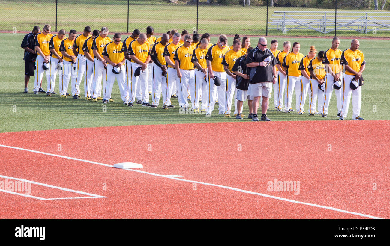 The U.S. Army men’s softball team bow their heads as the invocation is ...