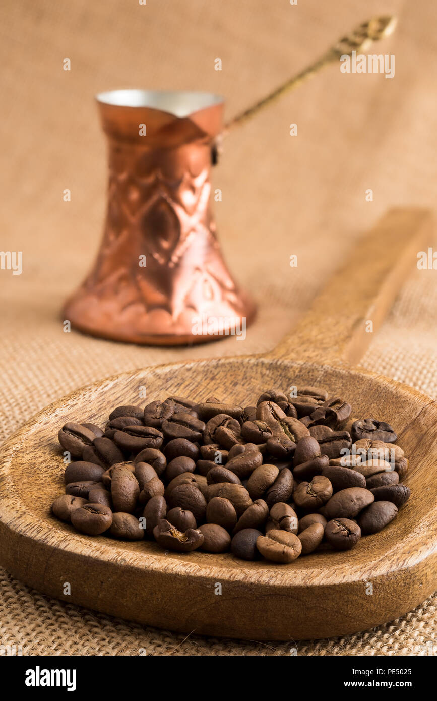 Roasted coffee beans in wooden ladle and traditional bronze coffee pot ...