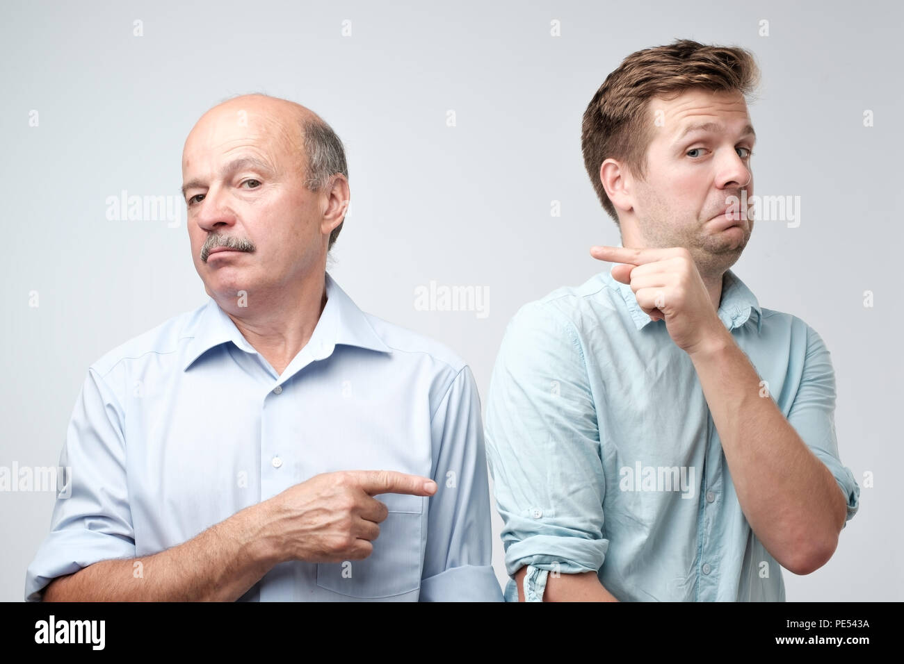 Portrait of two caucasian men pointing finger on each other. It was not ...