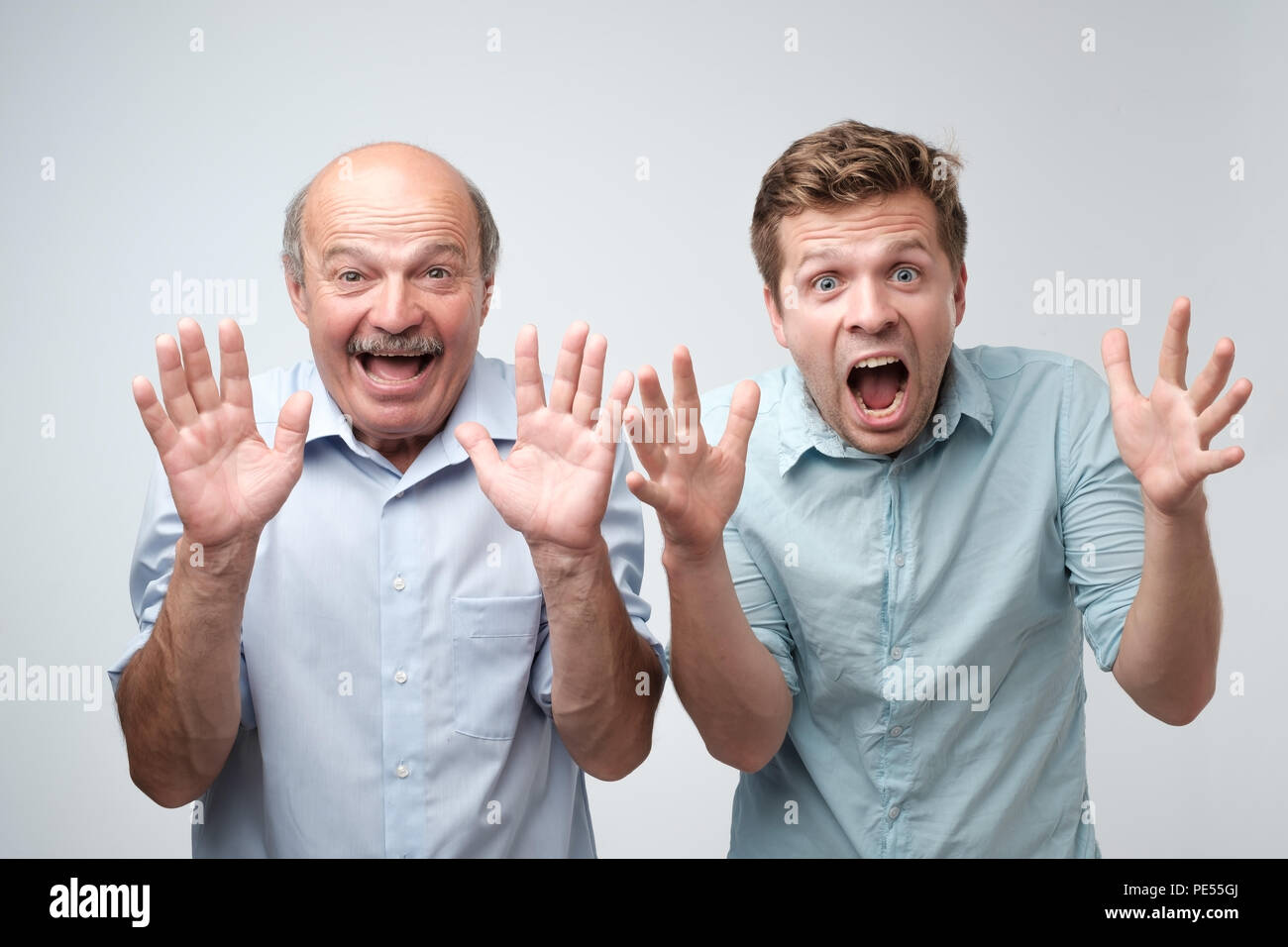 Curious shocked men, standing in casual shirts, isolated on pure ...
