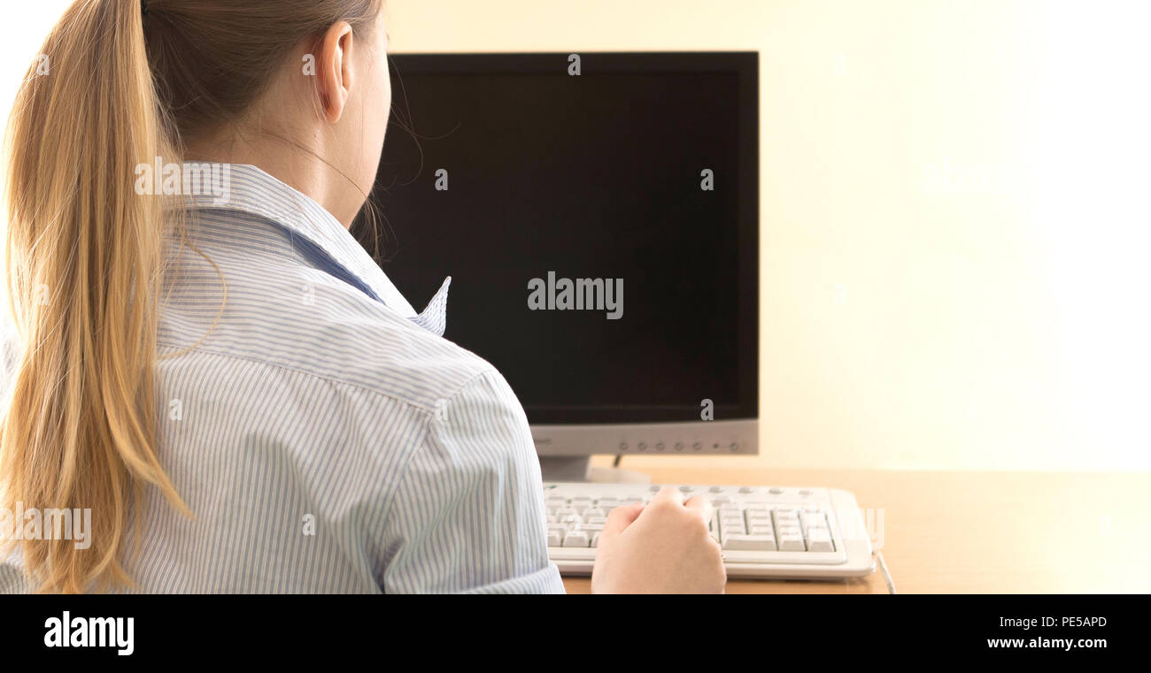 Young woman working on a desktop computer at her desk in the office ...