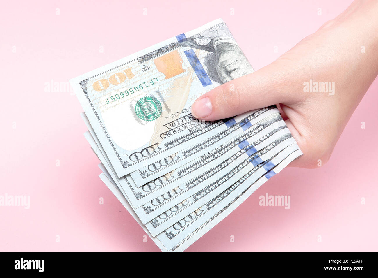 Pile of dollar s banknotes in female hand on pink background with copy ...