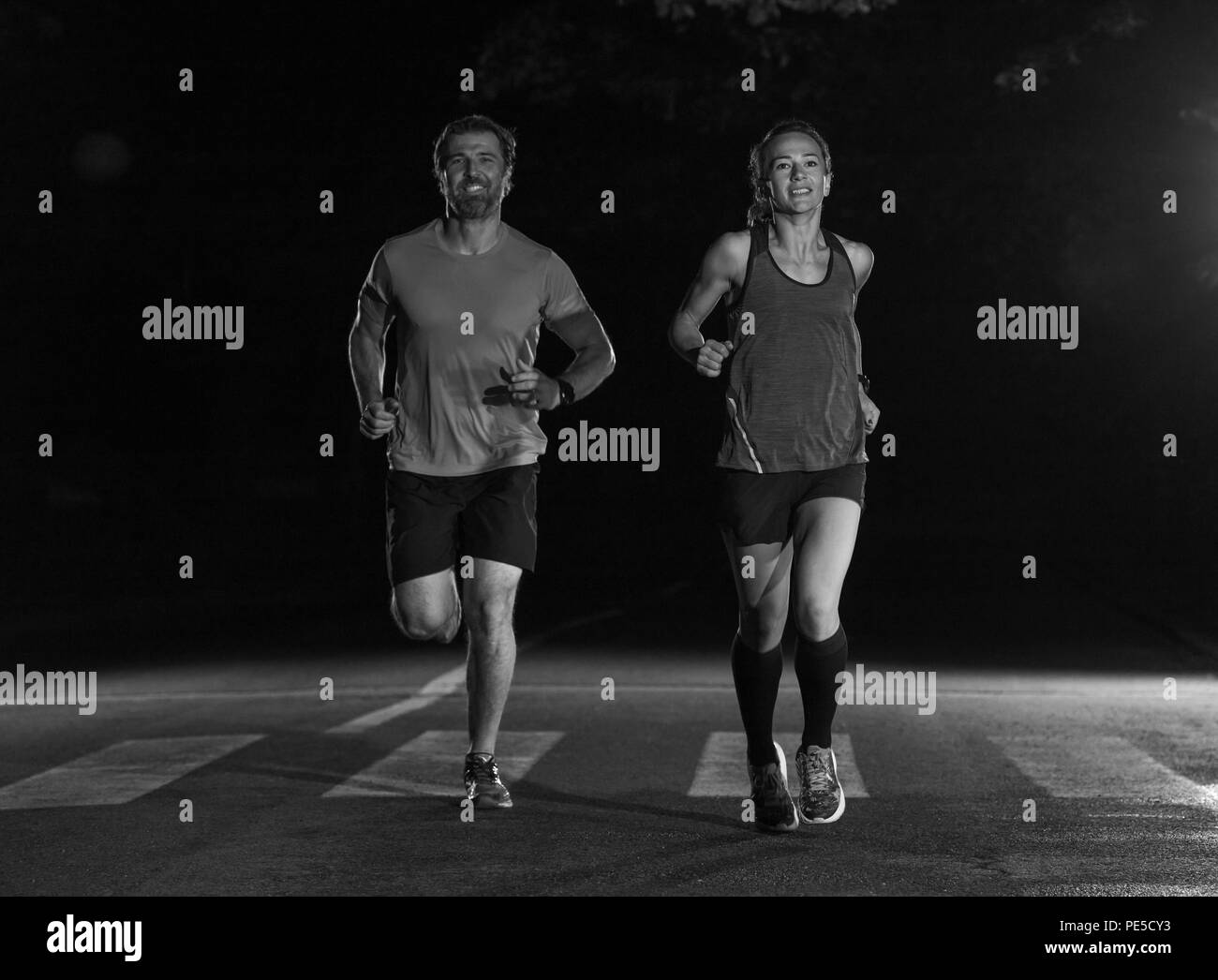 group of healthy people jogging in city park, runners team at night ...