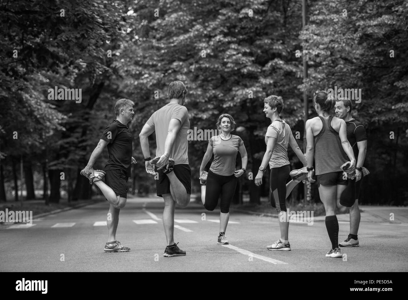 healthy runners team warming up and stretching in city park before ...