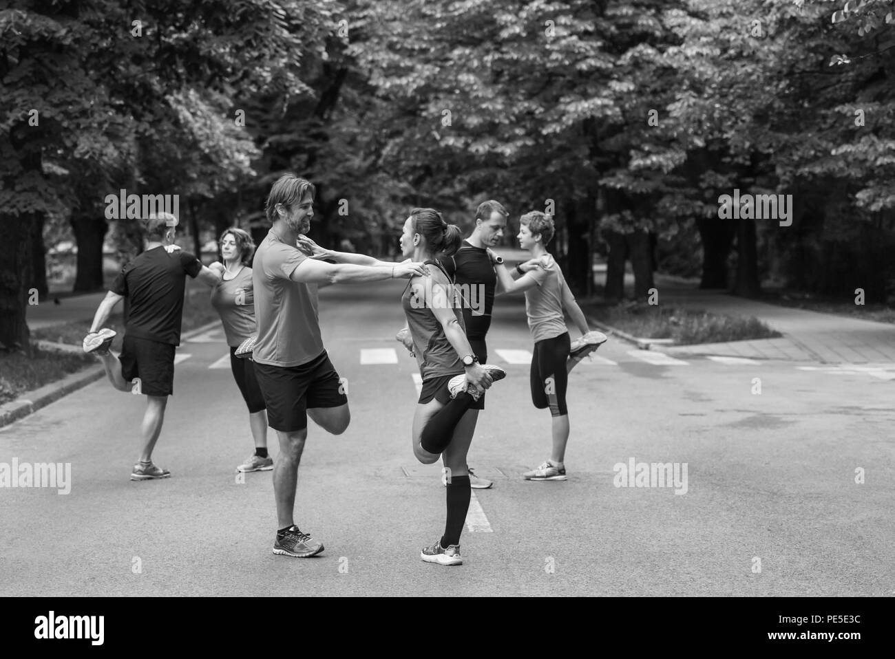 healthy runners team warming up and stretching in city park before ...