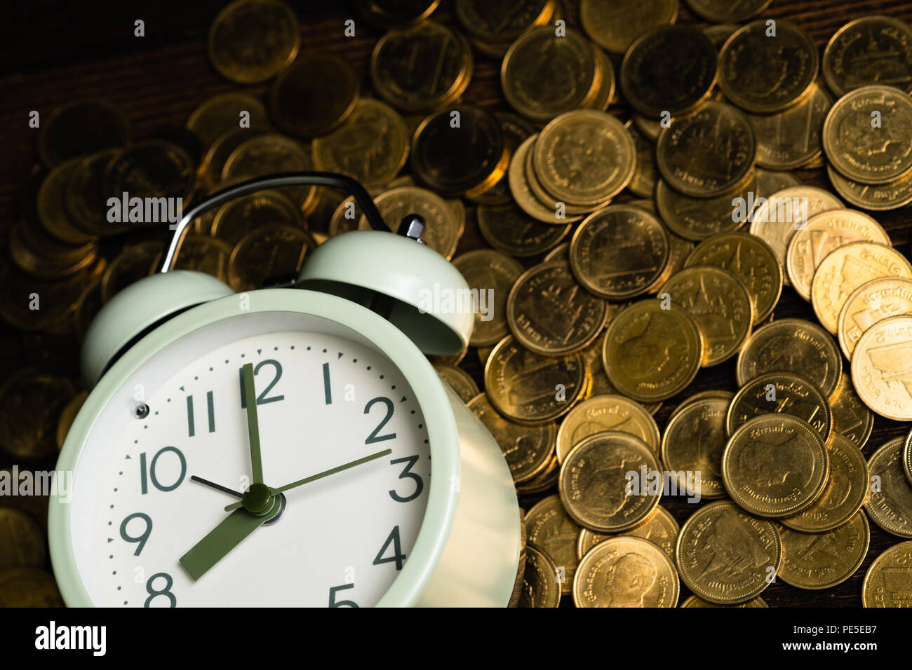 Alarm clock and coins stacks on working table in dark room, time for ...