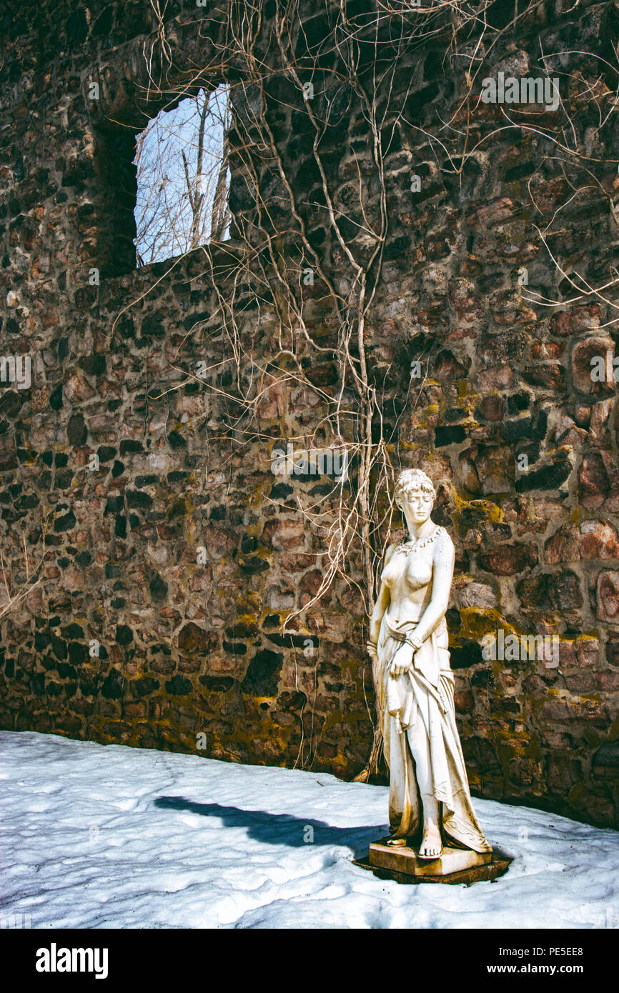Wall statue goddess in the sun. Vines and inner windows shine on her ...