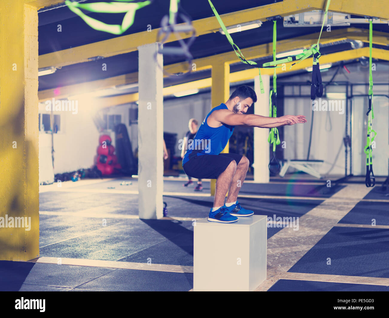 young athletic man training jumping on fit box at crossfitness gym ...