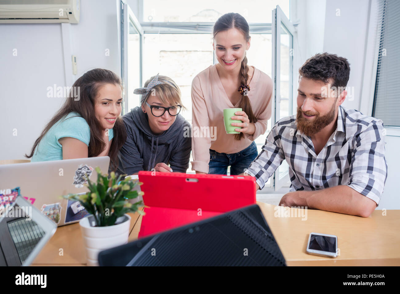 Four co-workers watching a business presentation in a modern shared ...