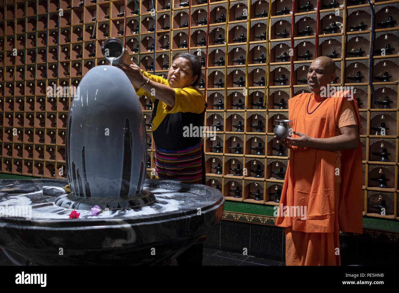 A Tibetan woman pours milk over a statue of the deity Shiva at a Hindu ...