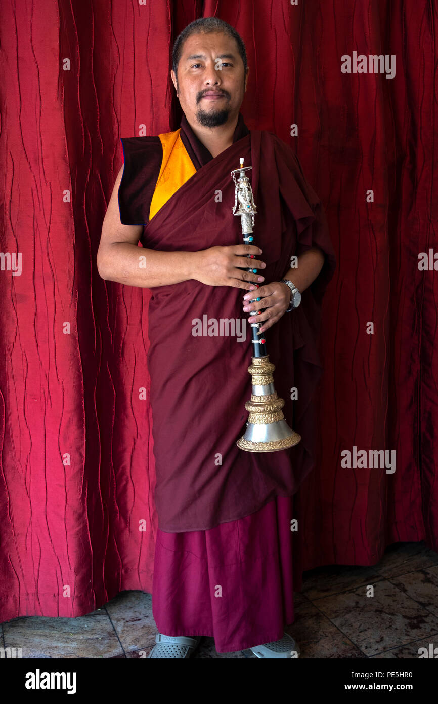 Posed portrait of a Buddhist monk from Bhutan and his gyaling horn at a ...