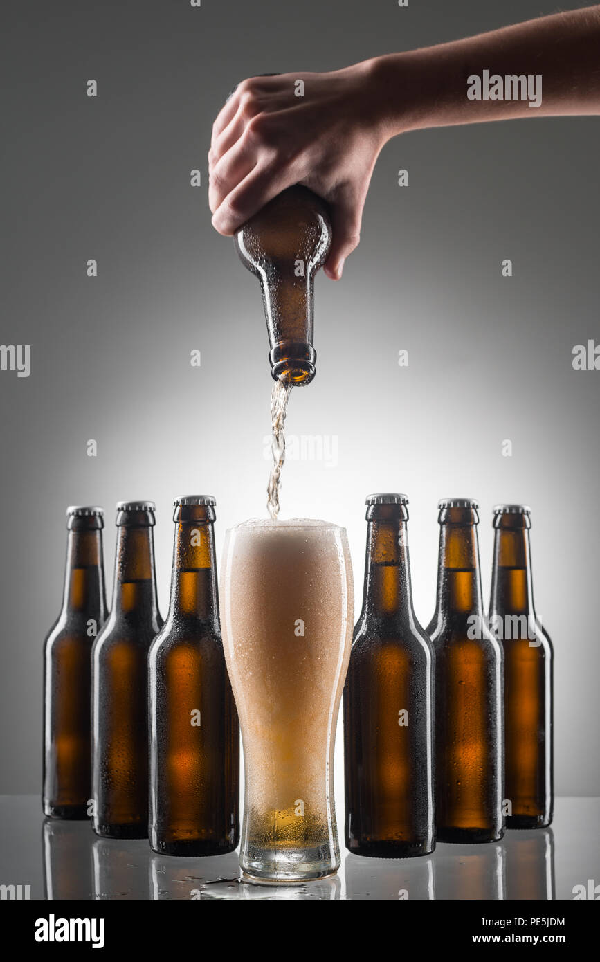 Male hand pouring beer into a glass and making too much foam head. Two ...