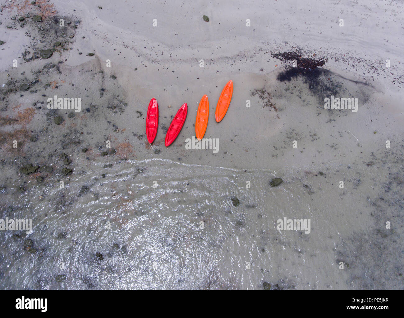 Orange and red kayaks on the beach shore Stock Photo - Alamy