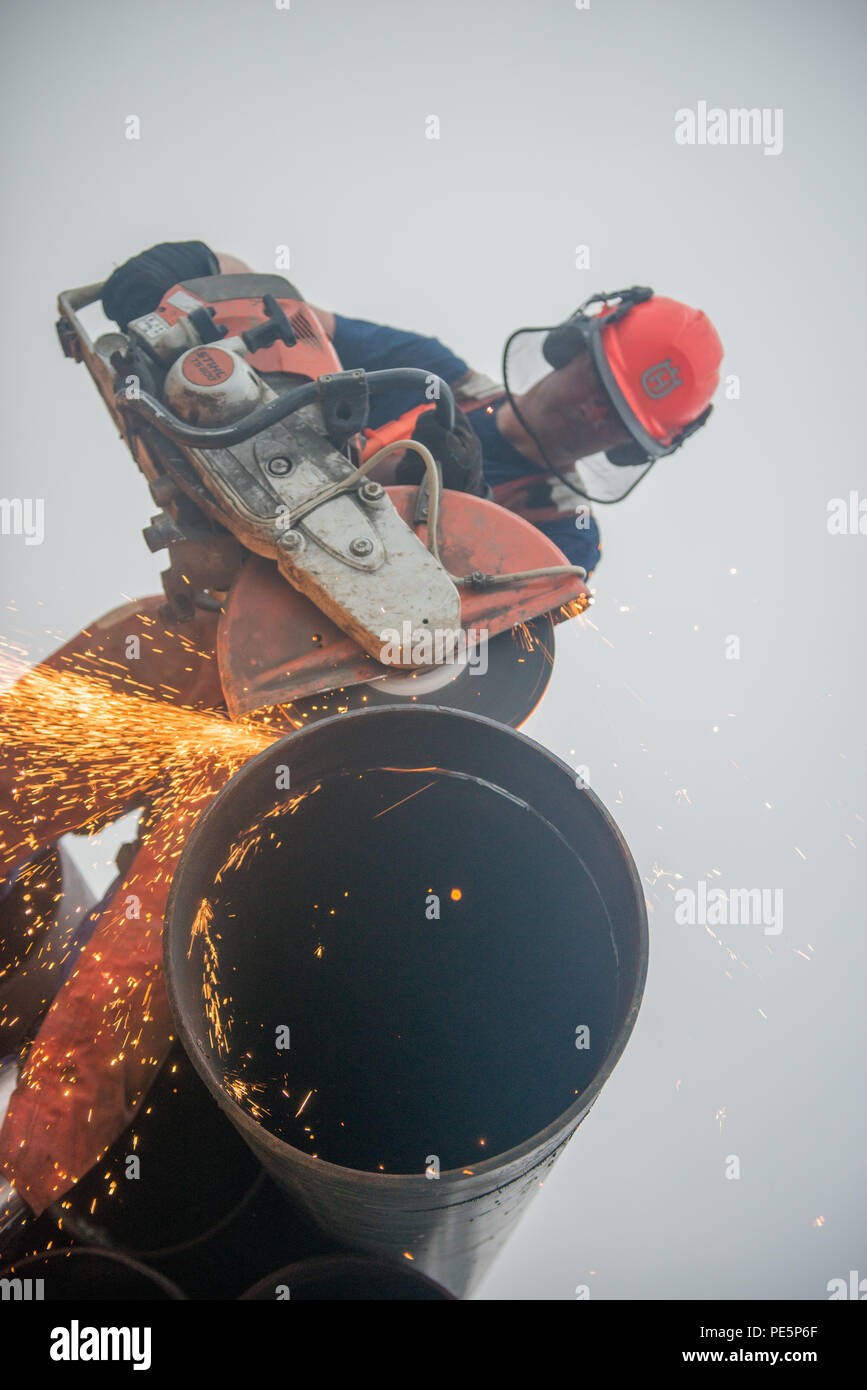 Fireman Apprentice John Perkins saws an 18’ metal pipe used as piling ...